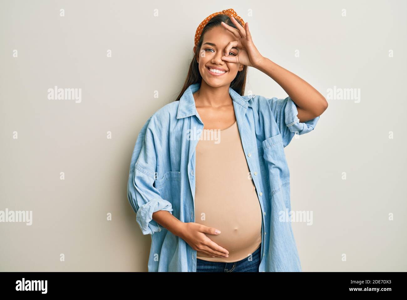 Beautiful hispanic woman expecting a baby, touching pregnant belly ...