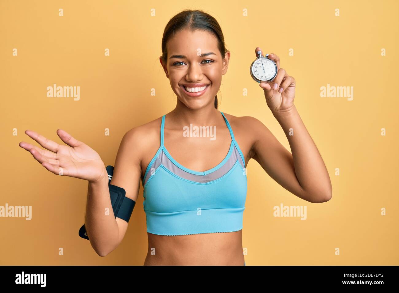 Beautiful hispanic woman wearing sportswear holding countdown clock ...