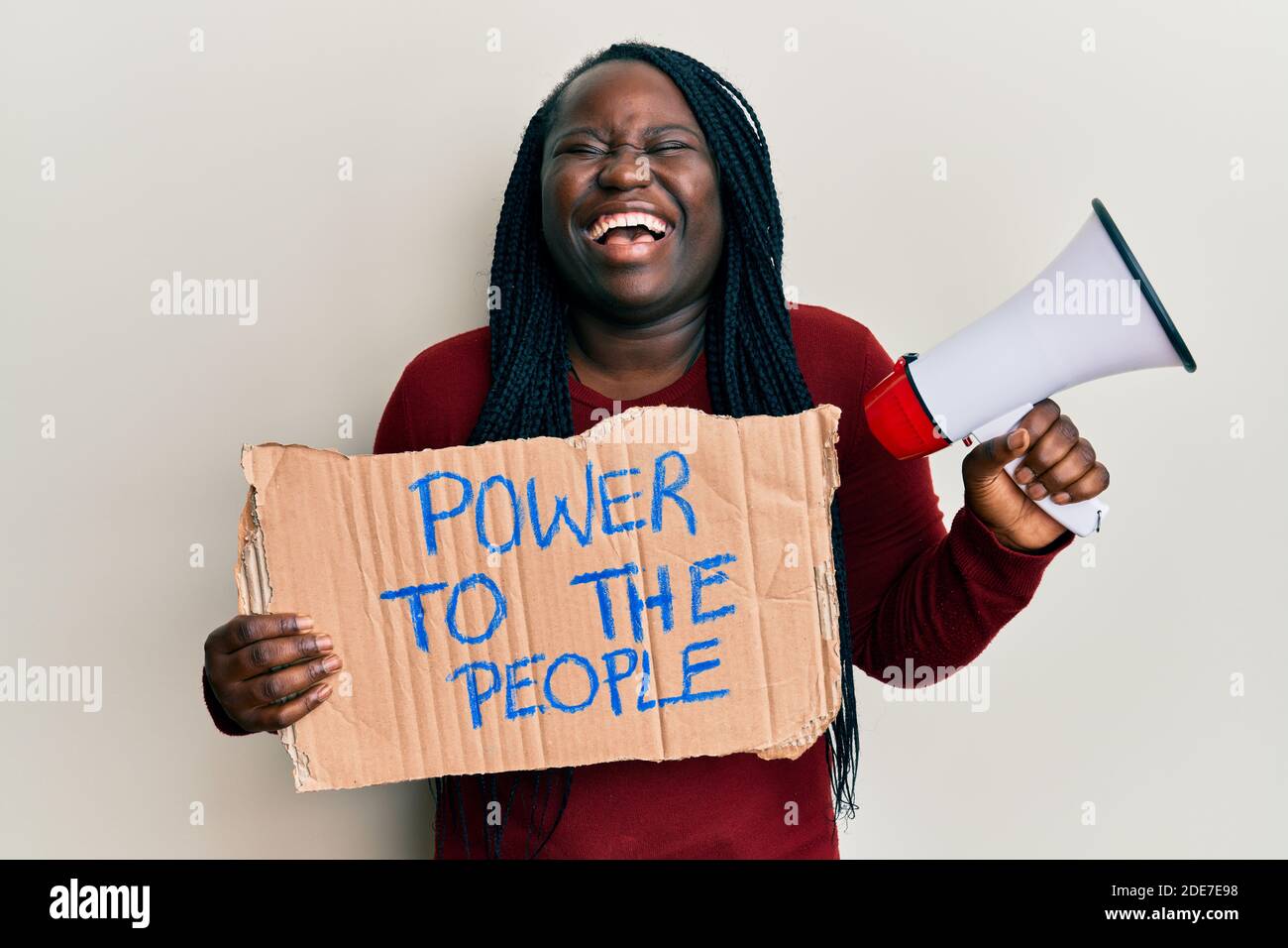 Young black woman with braids holding power to the people banner and ...