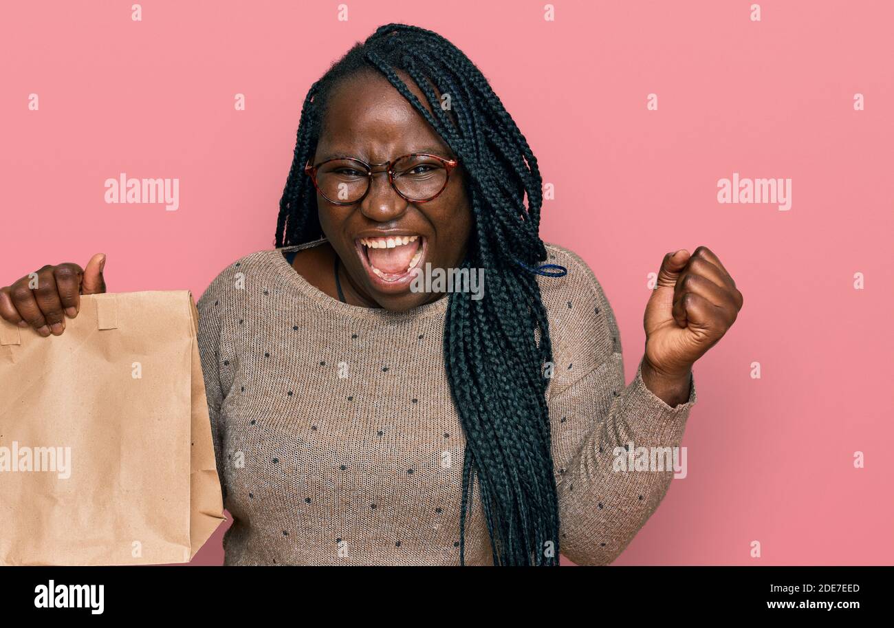 Young black woman with braids holding take away paper bag screaming ...