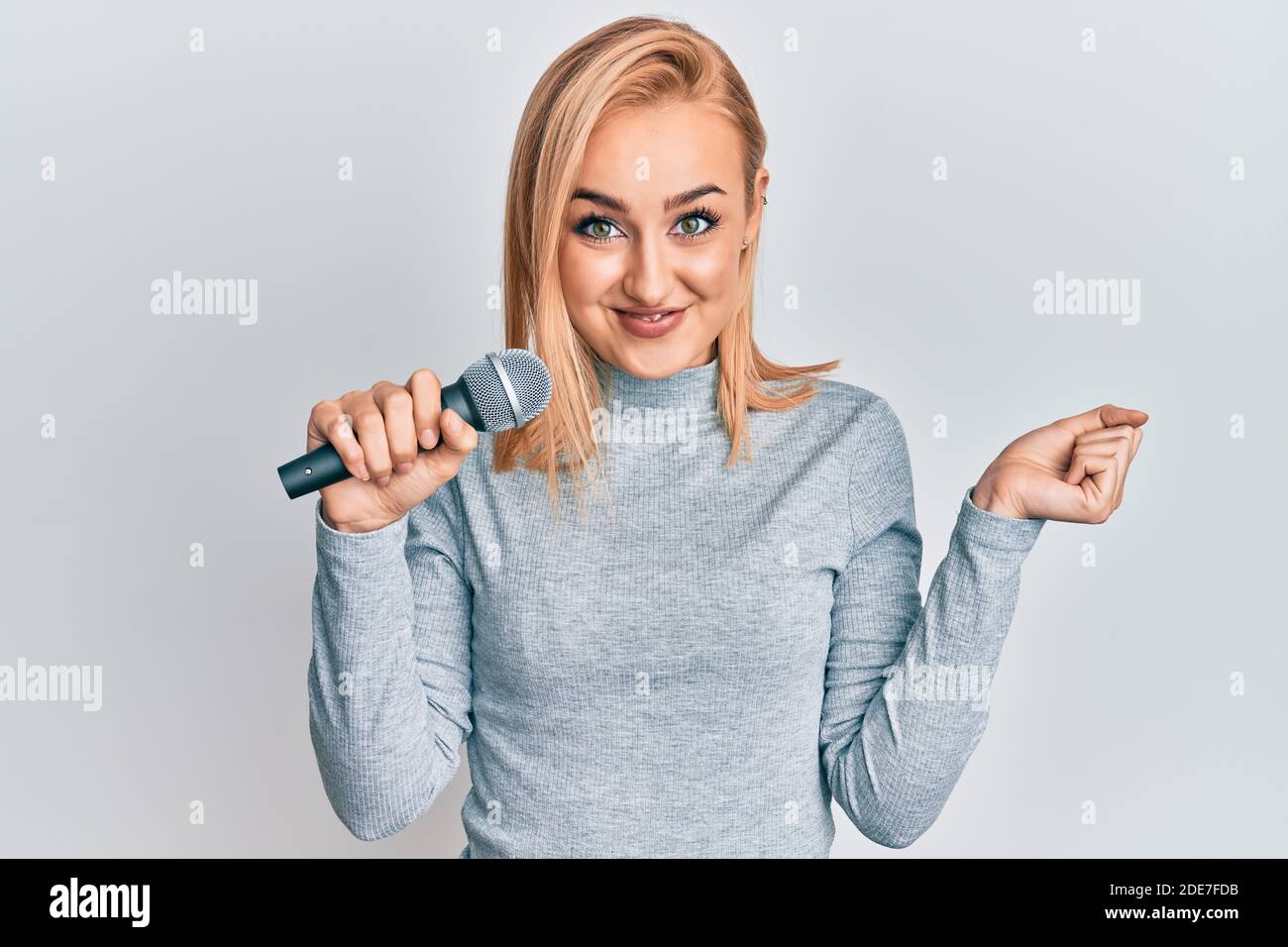 Beautiful caucasian woman singing song using microphone screaming proud ...