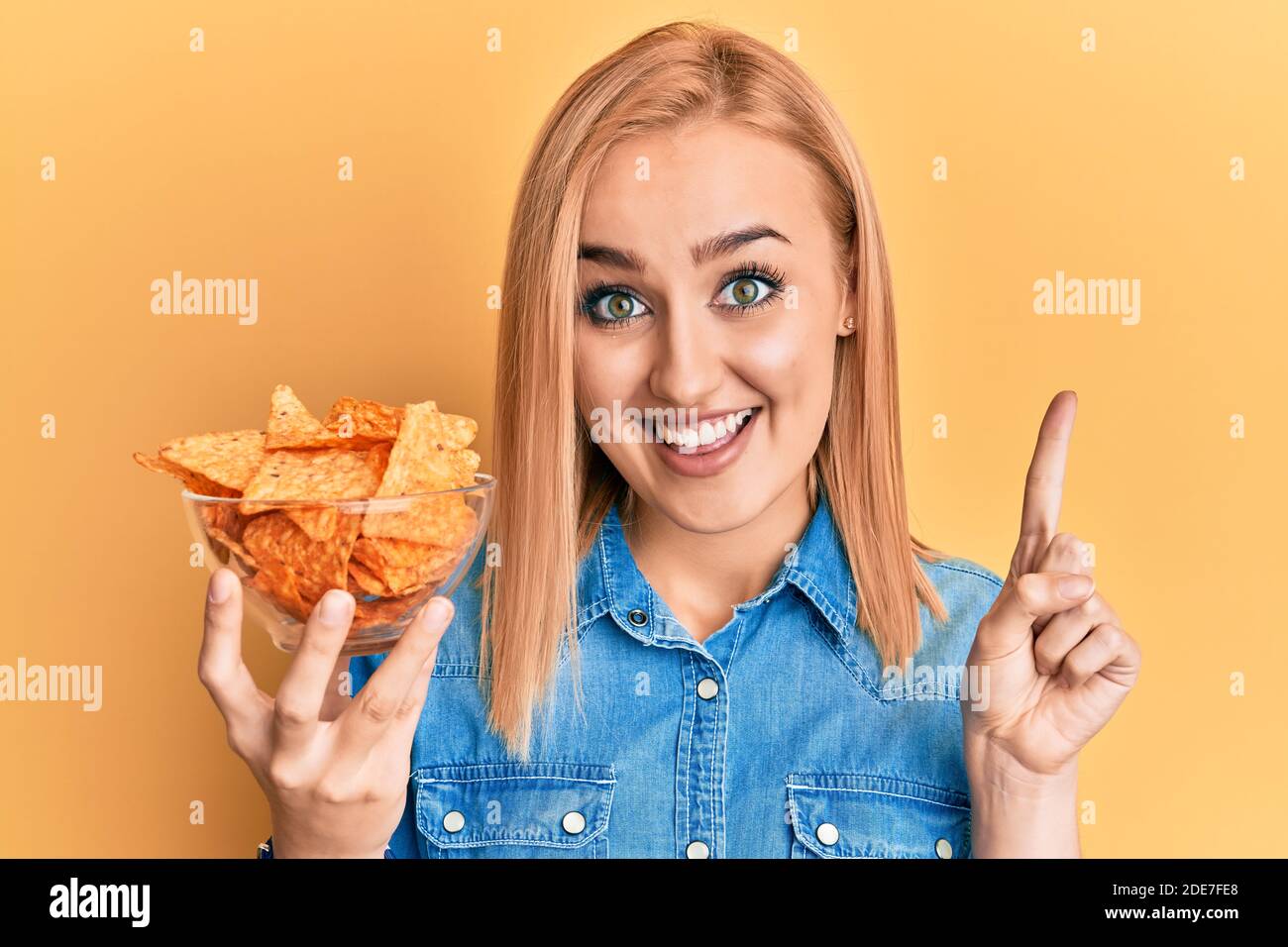 Beautiful caucasian woman holding nachos potato chips smiling with an ...