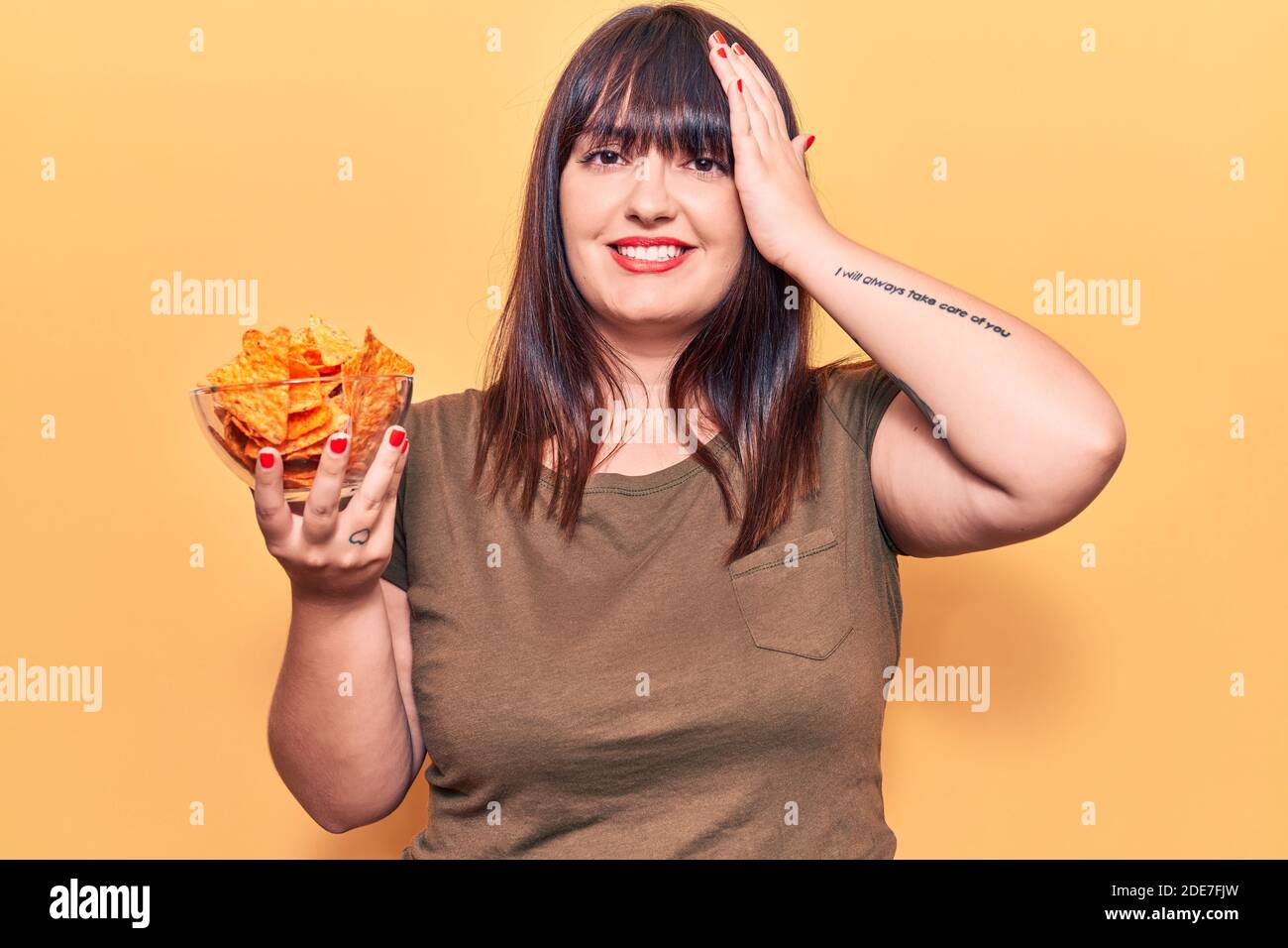 Young plus size woman holding nachos potato chips stressed and ...