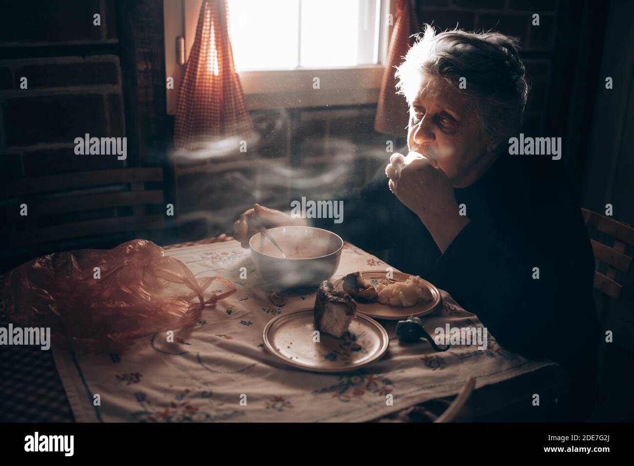 Elderly woman sitting alone at the table, eating a meal Stock Photo - Alamy