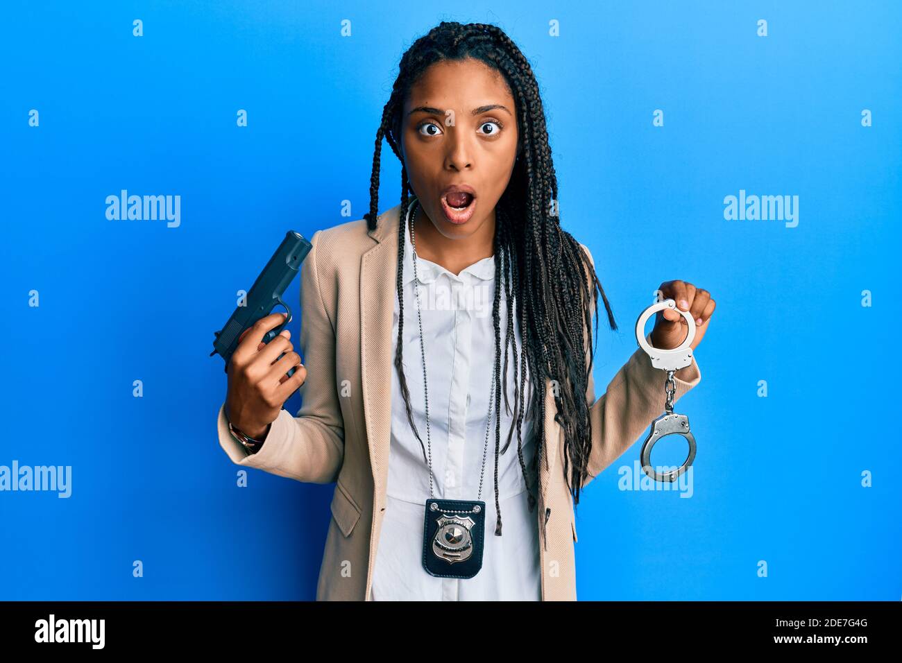 African american police woman holding gun and handcuffs afraid and ...