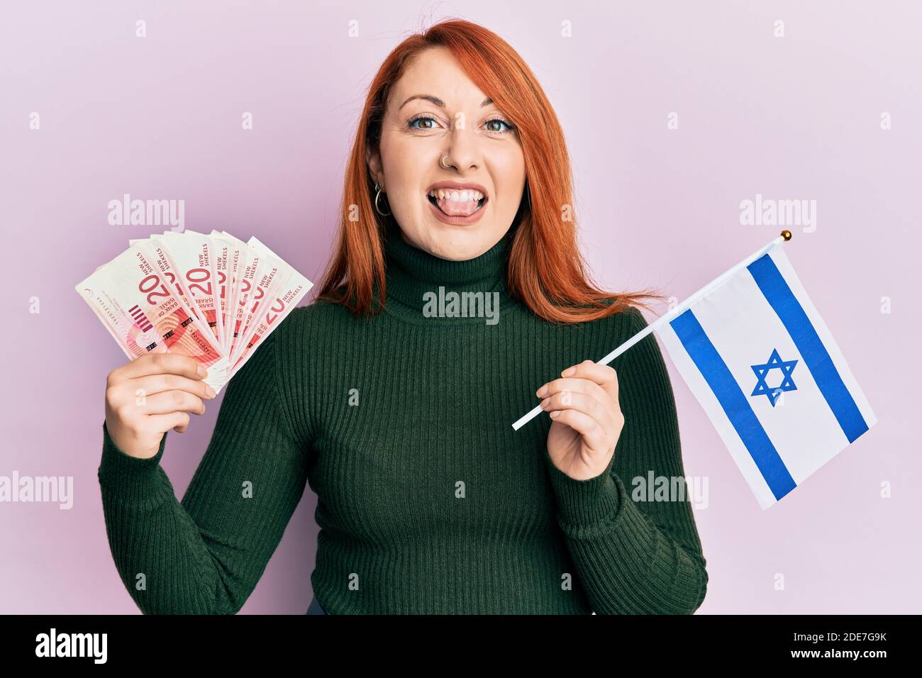 Beautiful redhead woman holding 20 shekels banknotes and israel flag ...