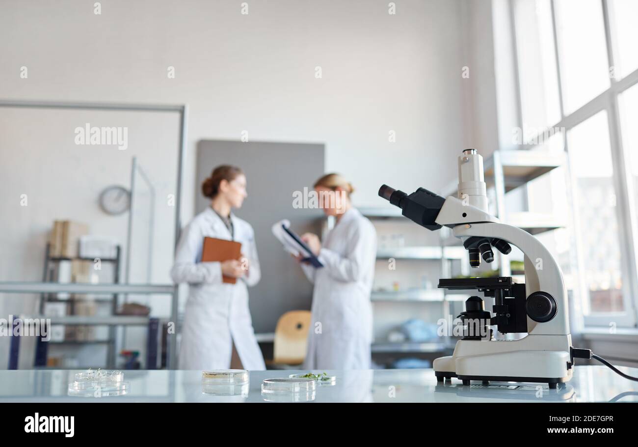Portrait of two female scientists discussing research while standing in ...