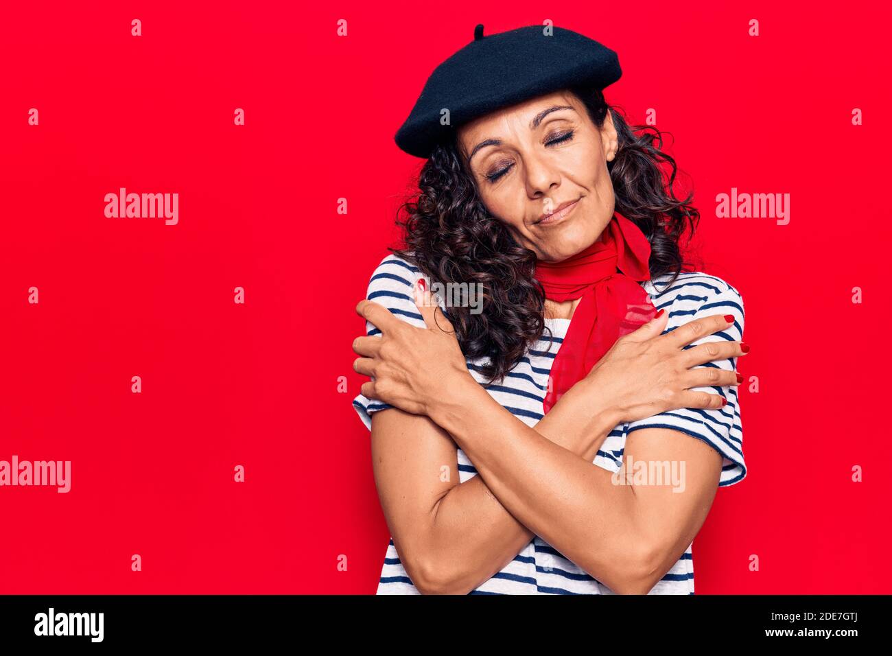 Middle age beautiful woman wearing french beret hugging oneself happy ...