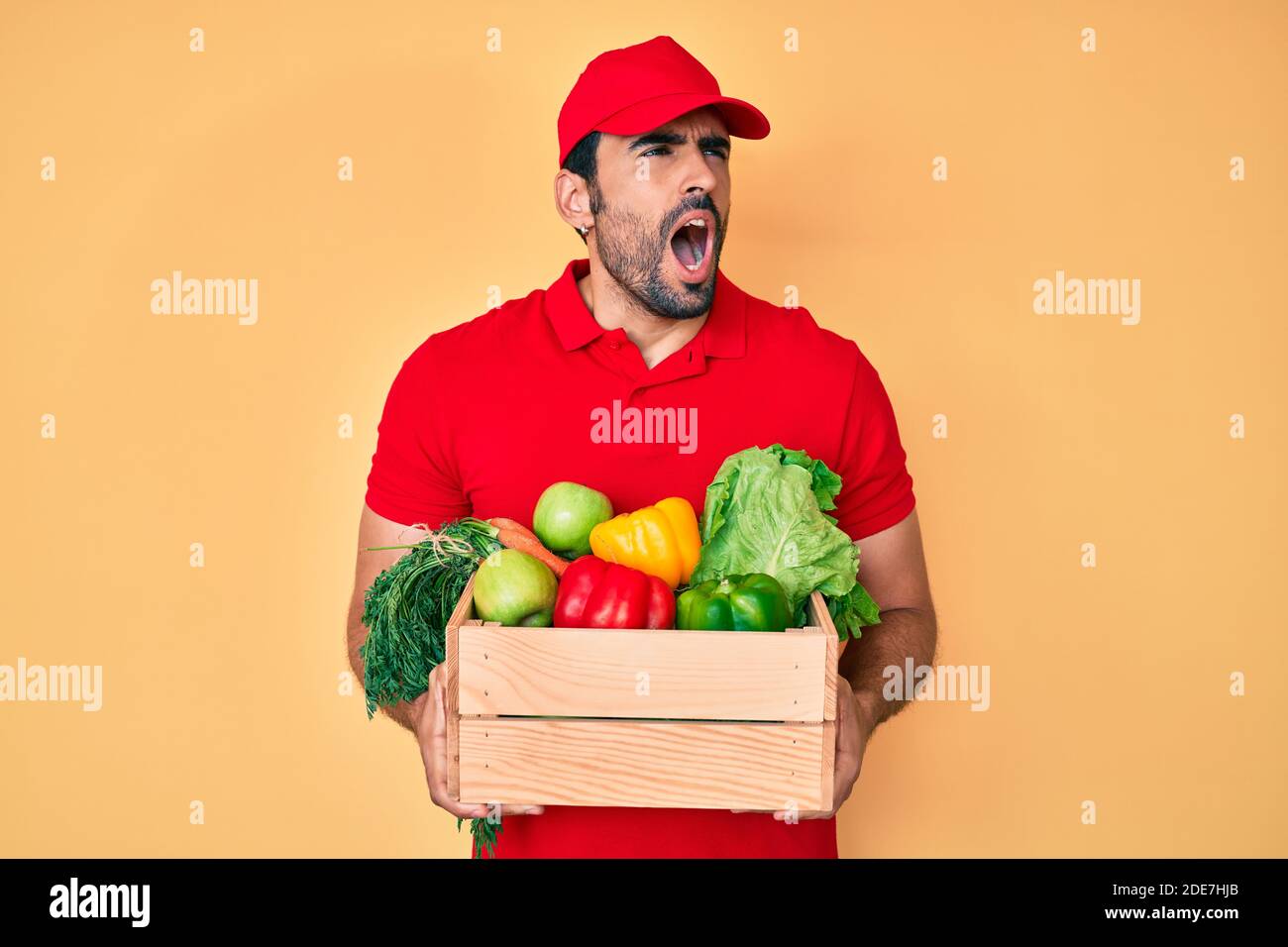 Handsome hispanic man with beard wearing uniform holding delivery food ...