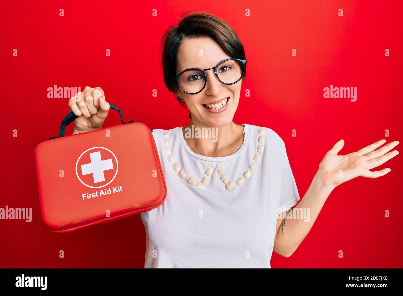 Young brunette woman with short hair holding first aid kit celebrating ...
