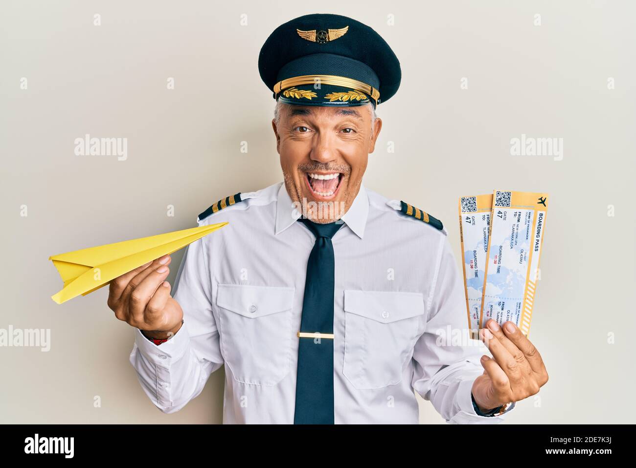 Handsome middle age mature pilot man holding paper plane and boarding ...
