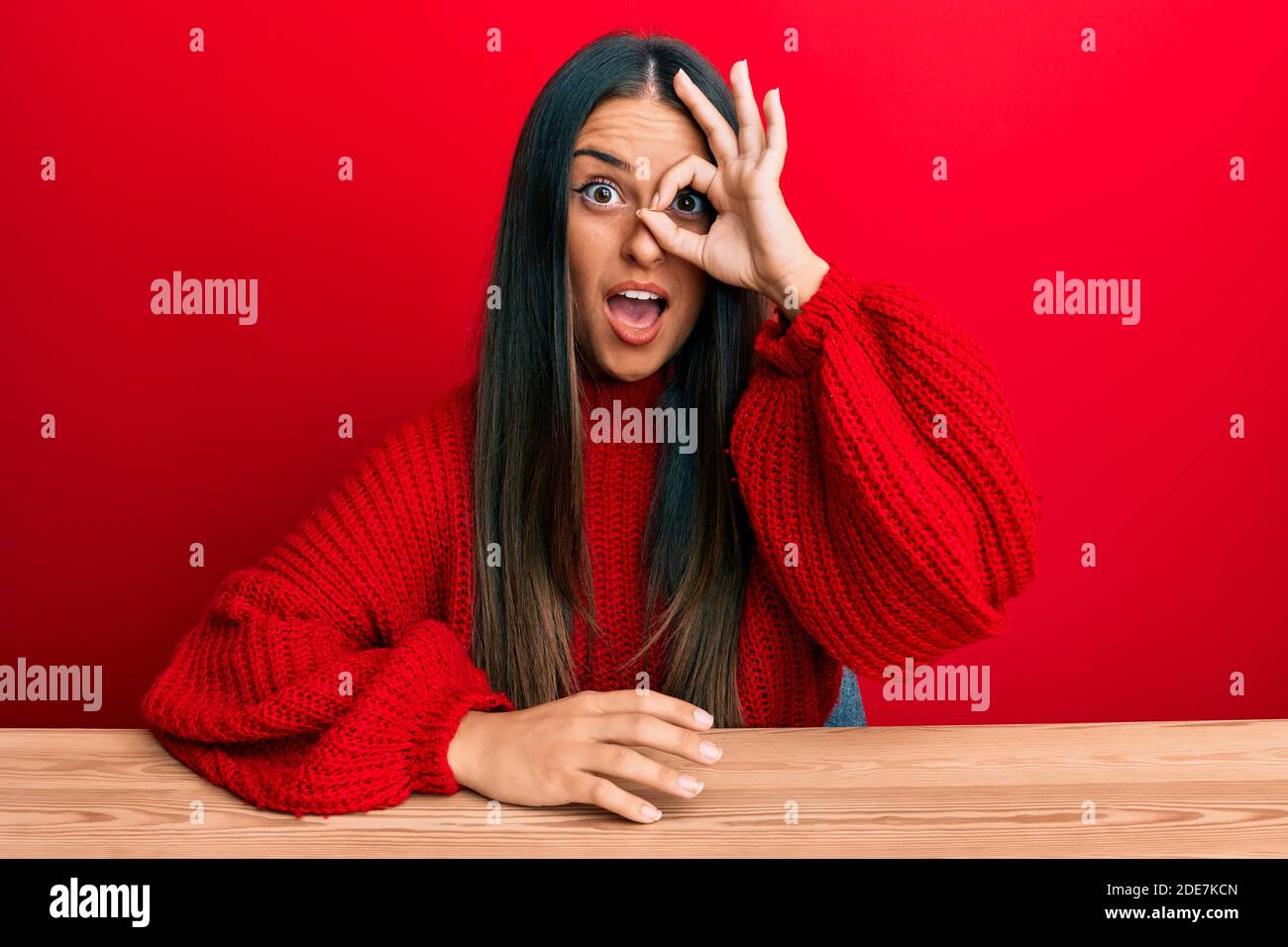 Beautiful hispanic woman wearing casual clothes sitting on the table ...