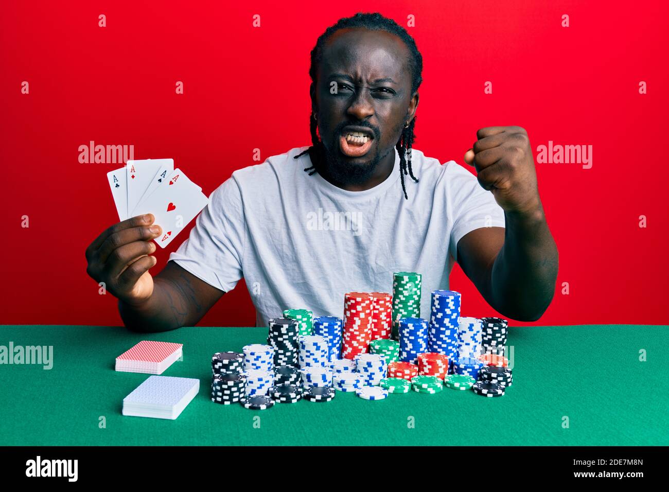 Handsome young black man playing poker holding cards annoyed and ...