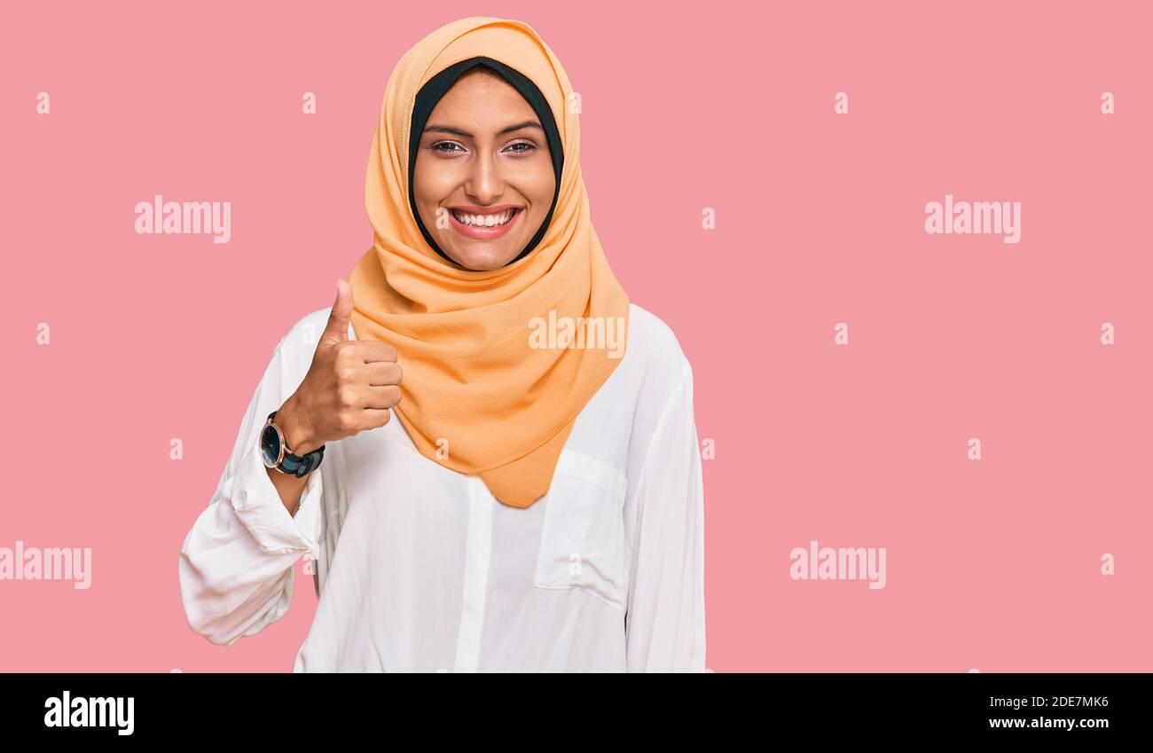 Young brunette woman wearing traditional islamic hijab scarf smiling ...