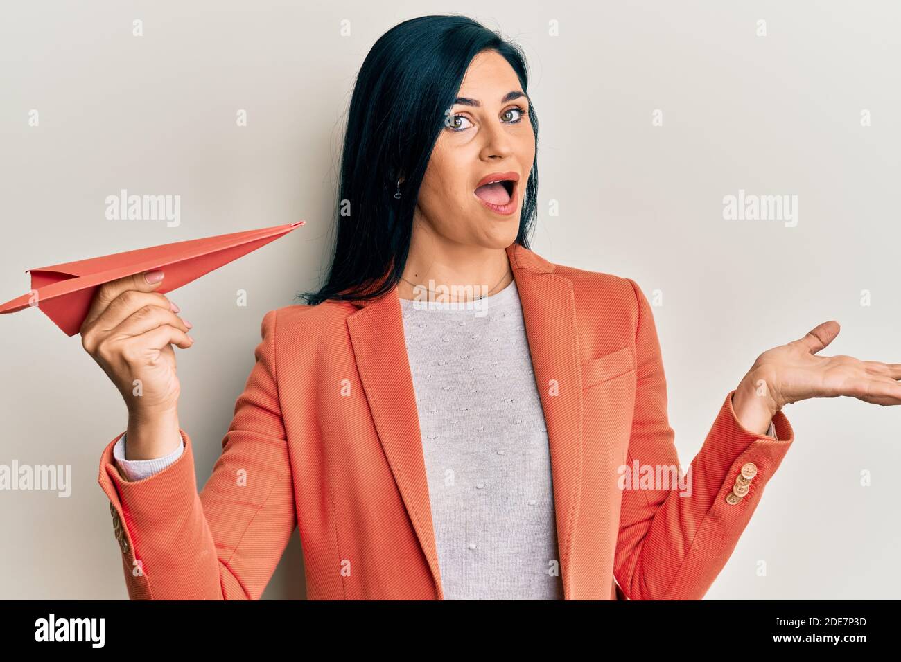 Young caucasian woman holding paper airplane celebrating achievement ...