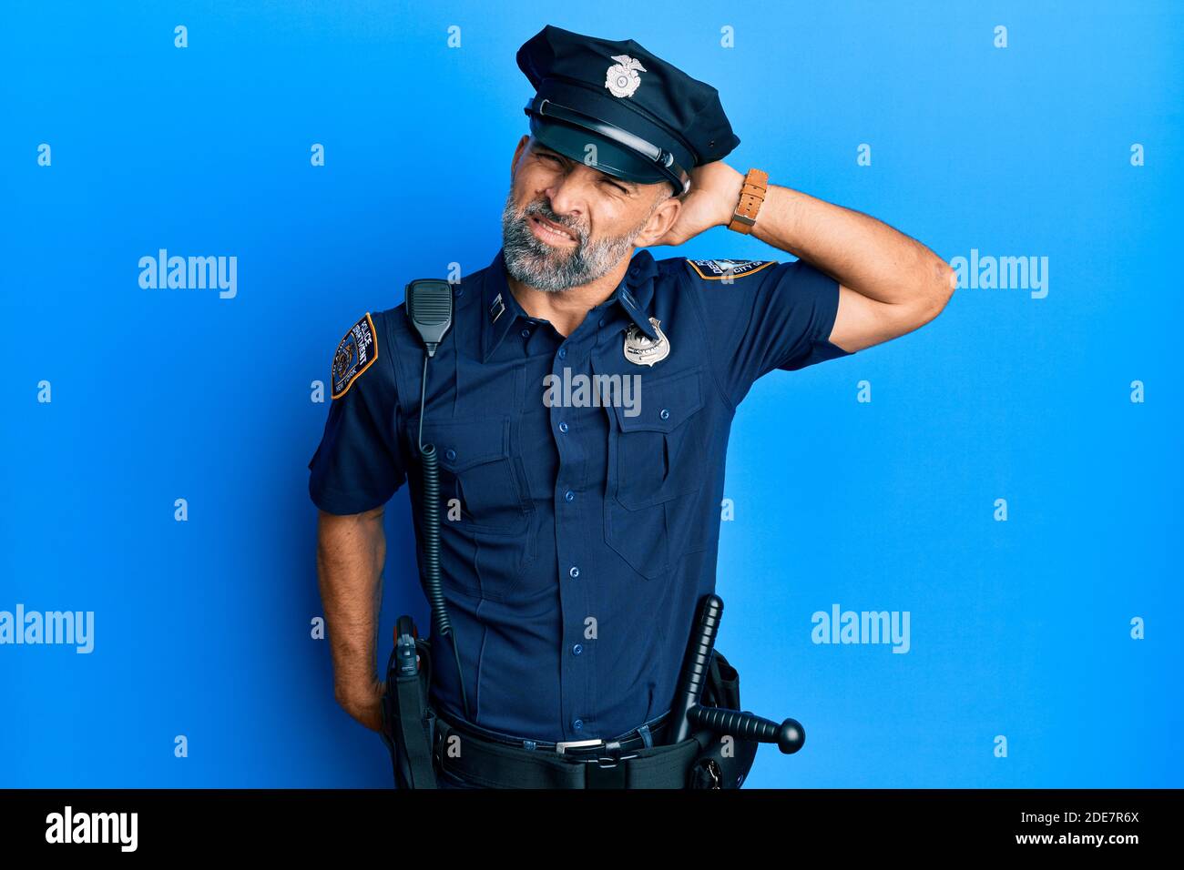 Middle age handsome man wearing police uniform suffering of neck ache ...