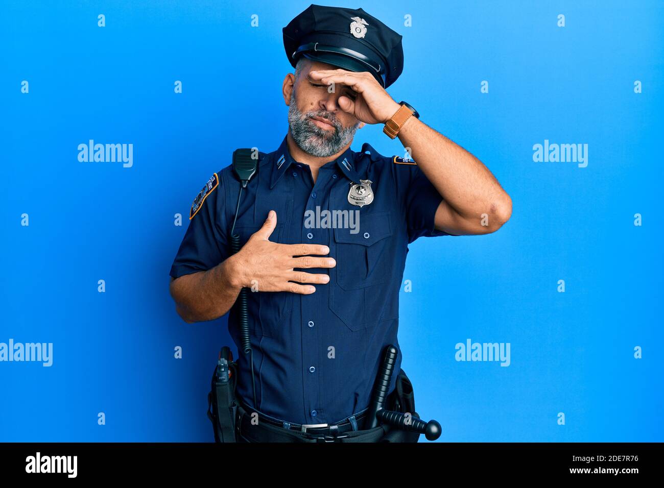 Middle age handsome man wearing police uniform touching forehead for ...