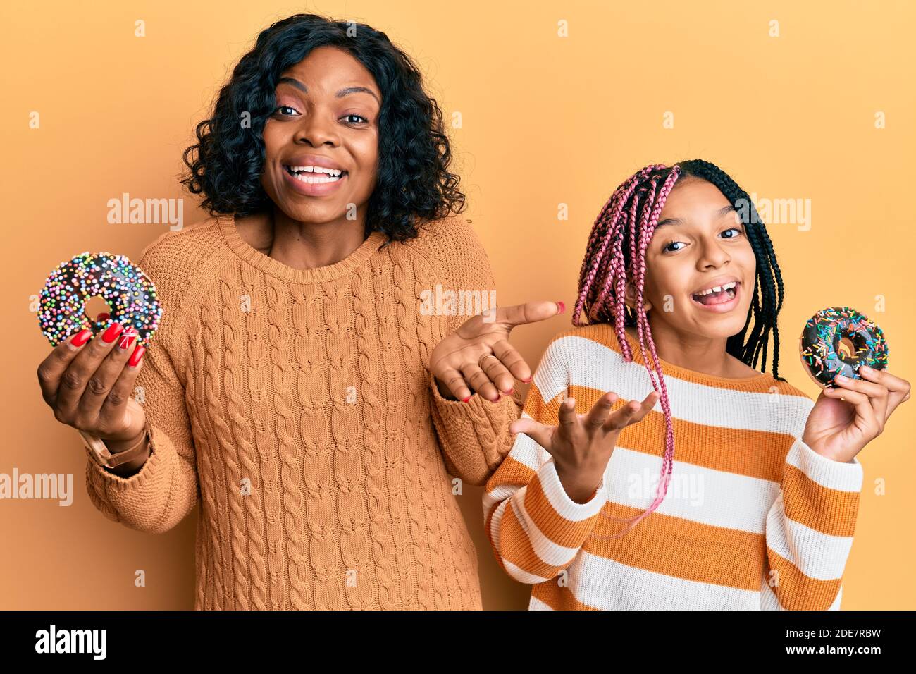 Beautiful african american mother and daughter holding donuts ...