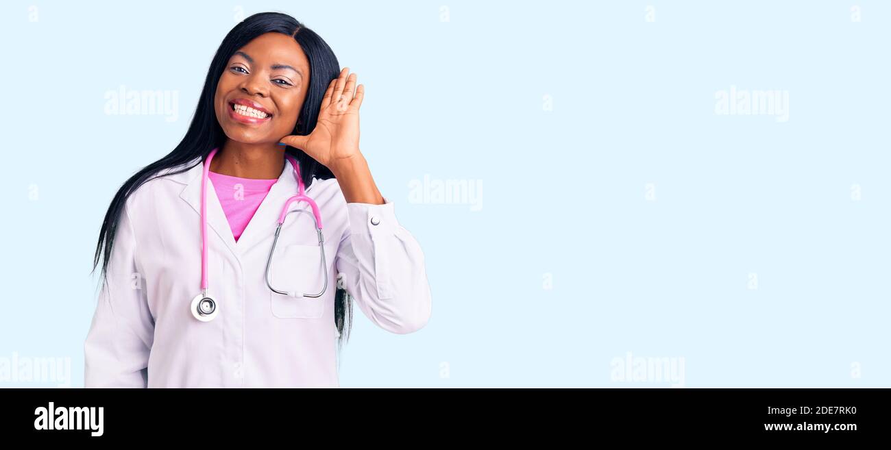 Young african american woman wearing doctor stethoscope waiving saying ...