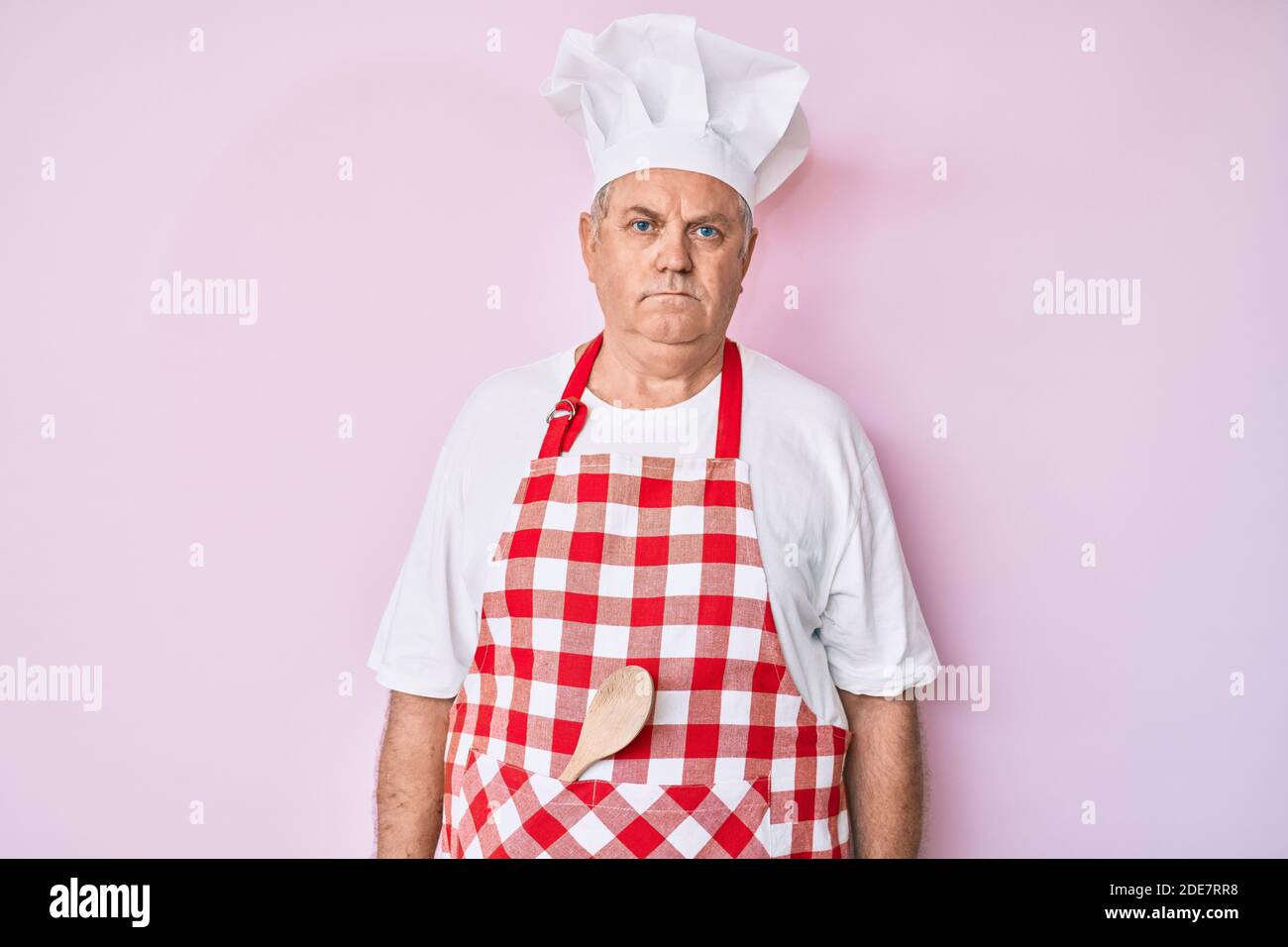 Senior grey-haired man wearing professional baker apron depressed and ...