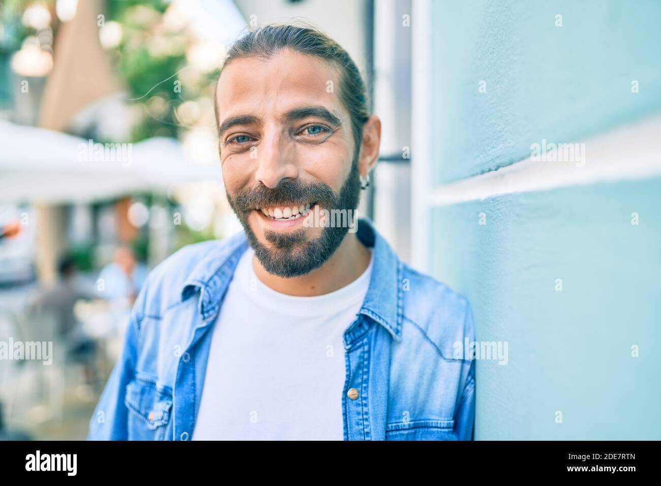 Young middle eastern man smiling happy leaning on the wall at the city ...