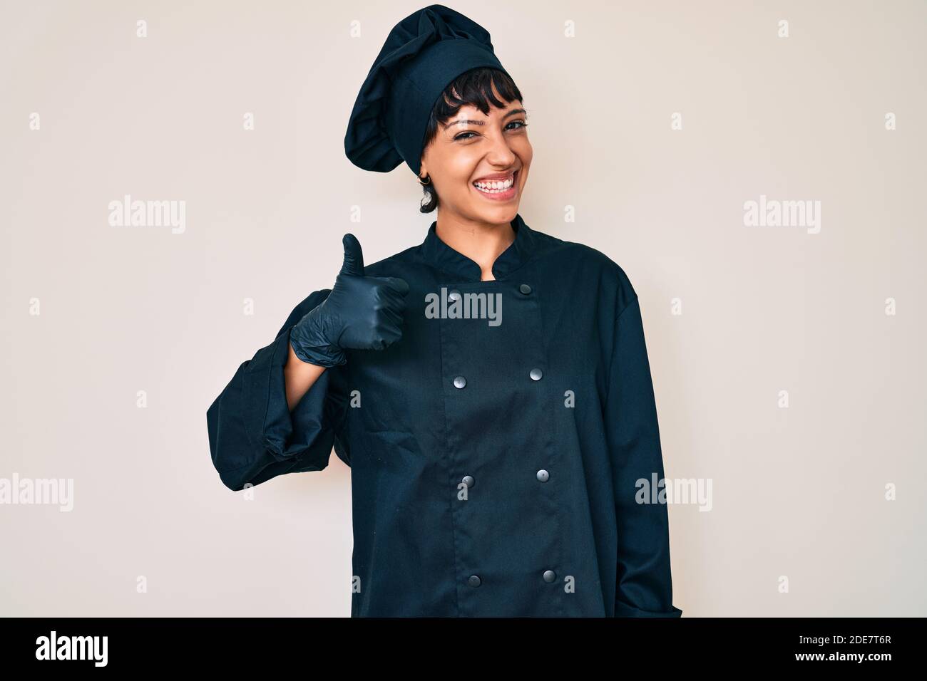 Beautiful brunettte woman wearing professional cook uniform doing happy ...
