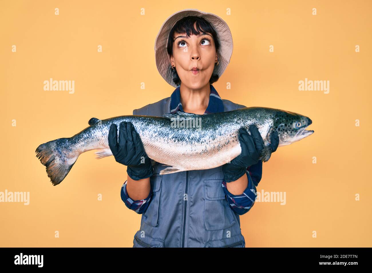 Beautiful brunettte fisher woman showing raw salmon making fish face ...