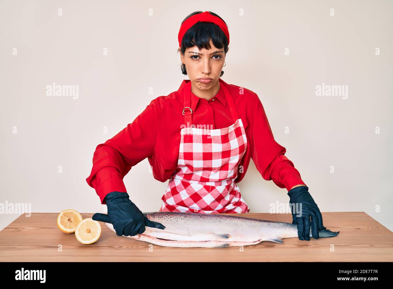 Beautiful brunettte woman fishmonger selling fresh raw salmon depressed ...
