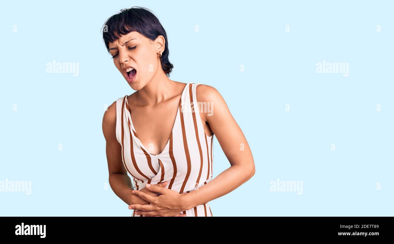 Young brunette woman with short hair wearing summer outfit with hand on ...