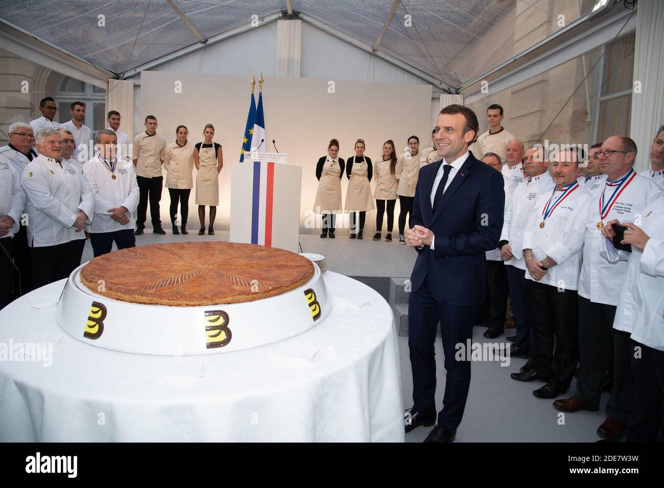 French President Emmanuel Macron stands by a traditional epiphany cake ...