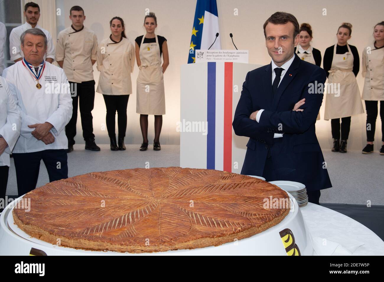 French President Emmanuel Macron stands by a traditional epiphany cake ...