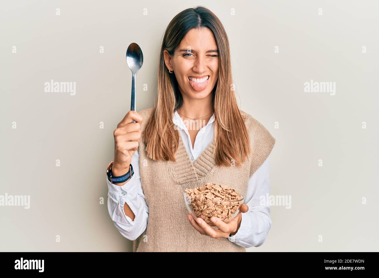 Brunette young woman eating healthy whole grain cereals with spoon ...