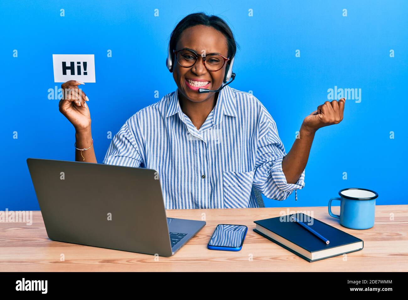 Young african woman wearing operator headset holding hi word screaming ...