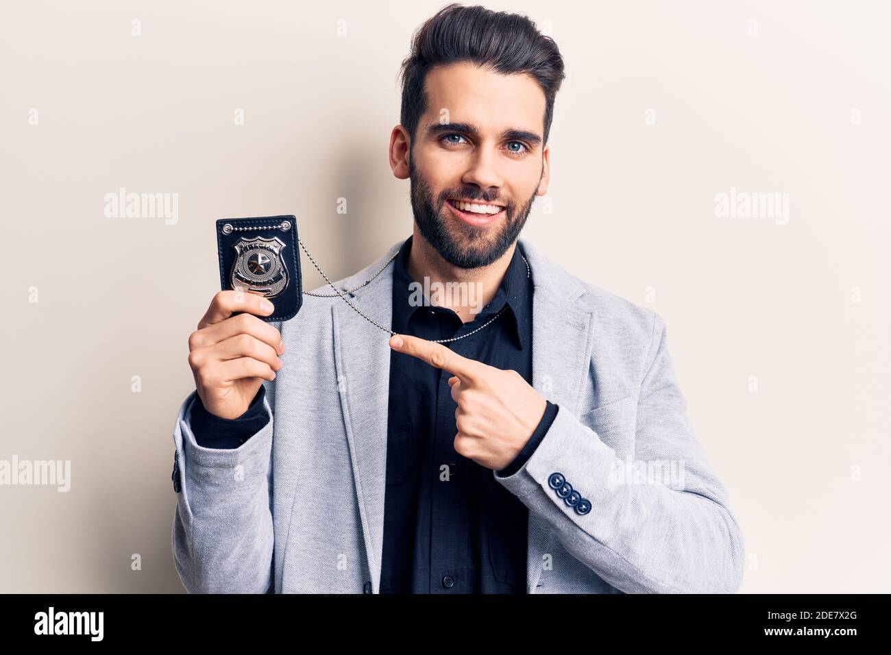 Young handsome man with beard holding police badge smiling happy ...