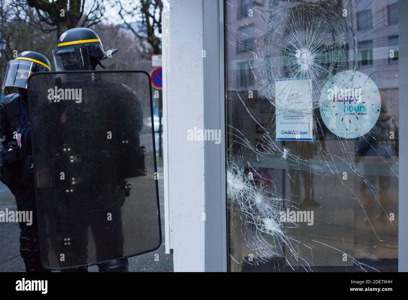 A police officer stands next to a broken bank window during a yellow ...