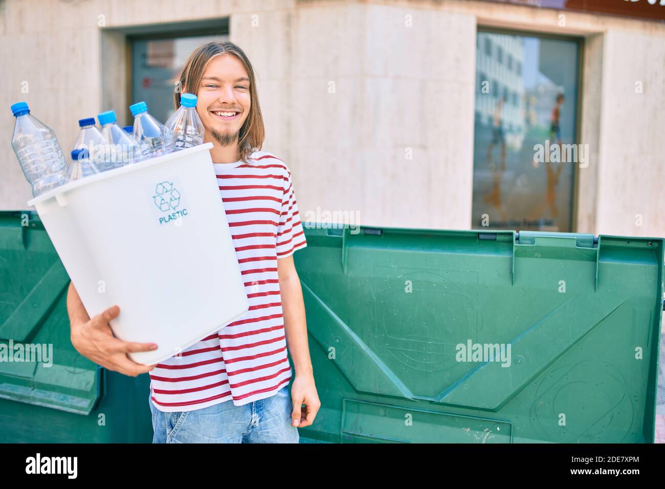 Young caucasian man with blond long hair and beard recycling plastic ...