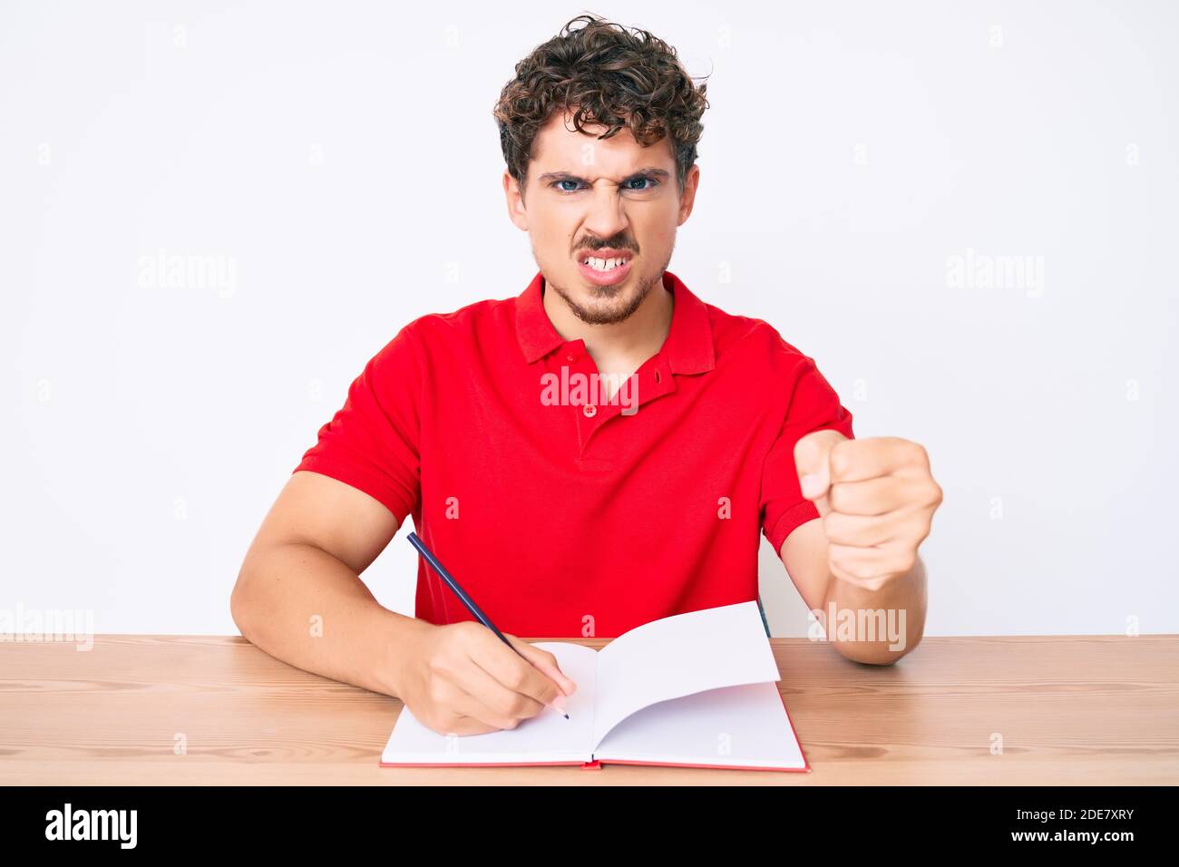 Young caucasian man with curly hair writing notebook sitting on the ...