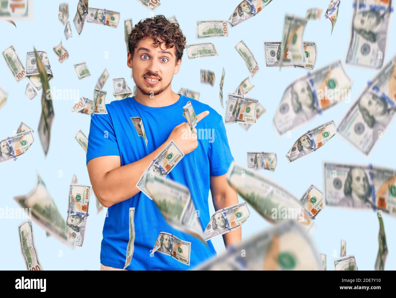 Young handsome man with curly hair wearing casual clothes pointing ...