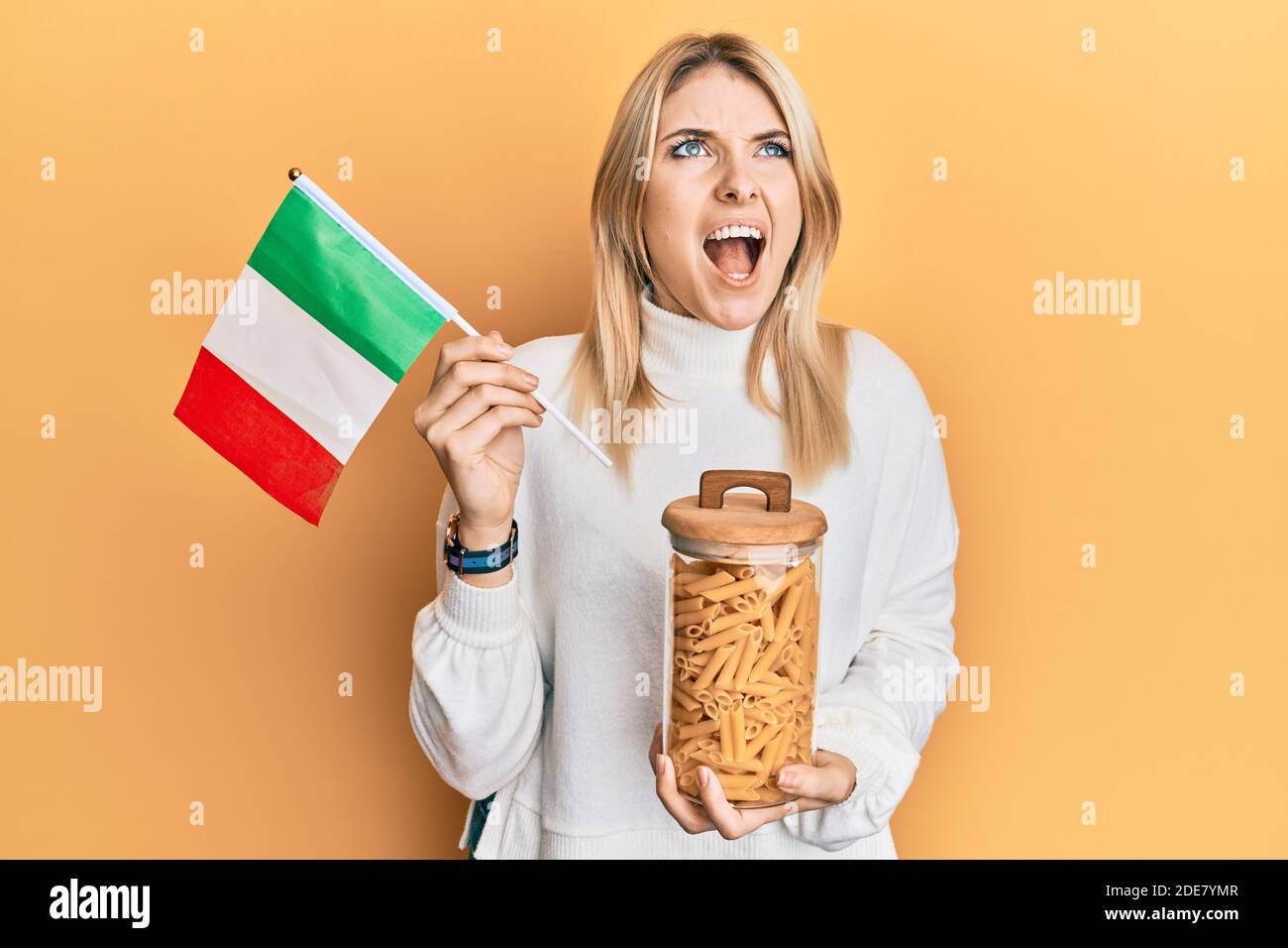 Young caucasian woman holding jar of macaroni pasta and italian flag ...