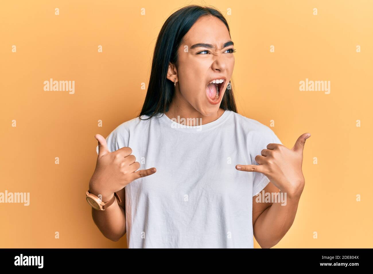 Young asian woman doing shaka sign with hands angry and mad screaming ...