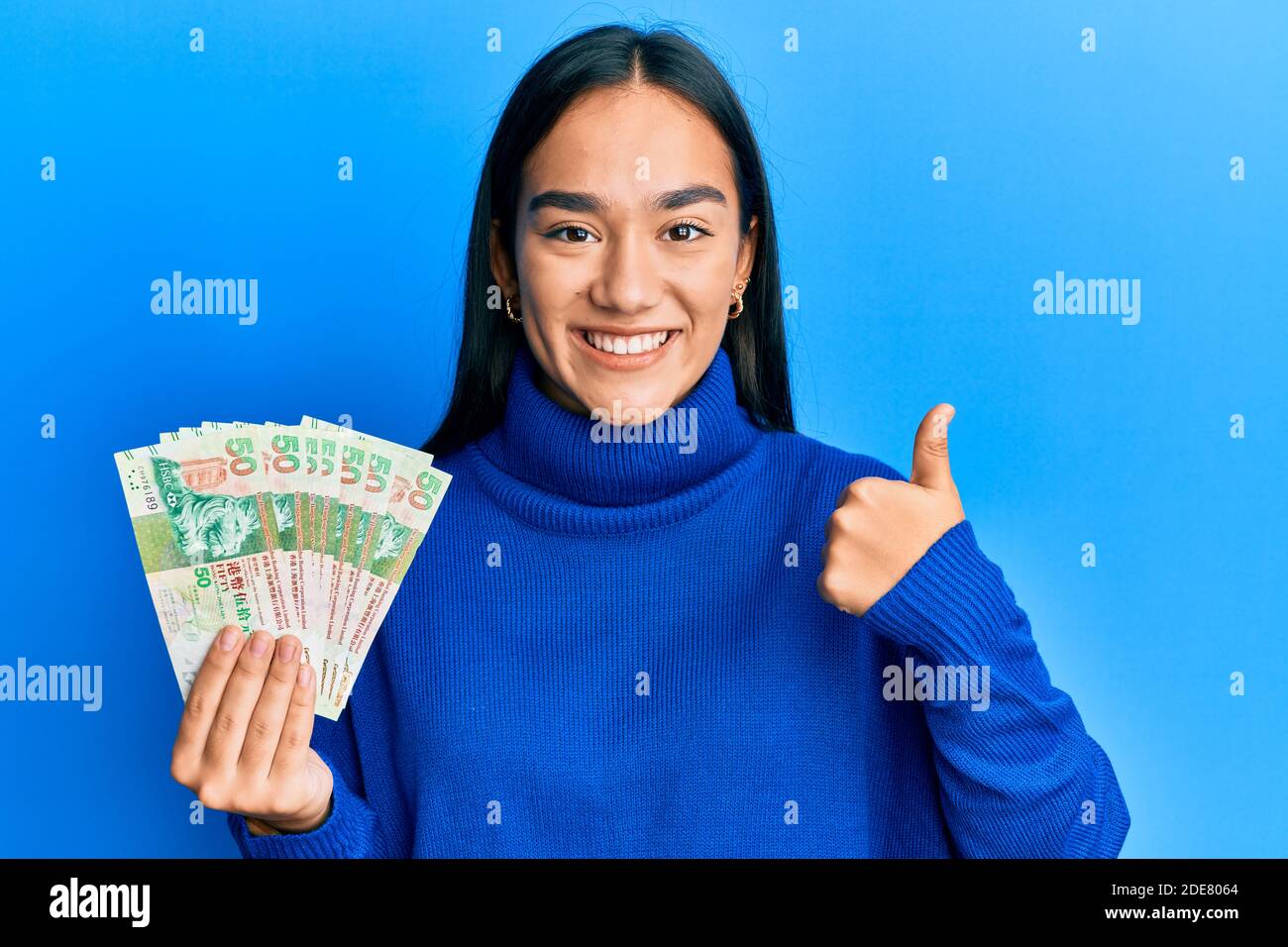Young asian woman holding 50 hong kong dollars banknotes smiling happy ...