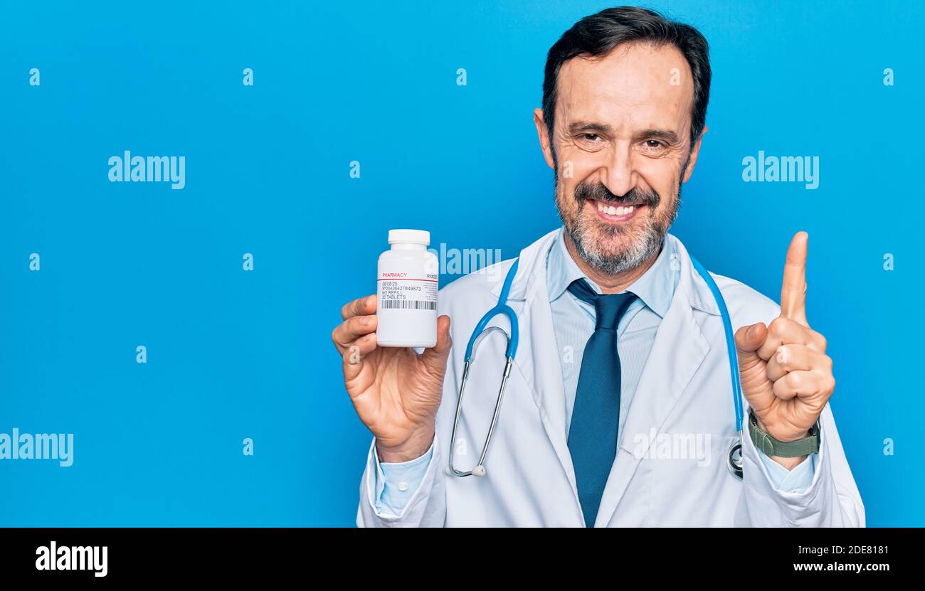 Middle age handsome doctor man wearing stethoscope holding bottle of ...