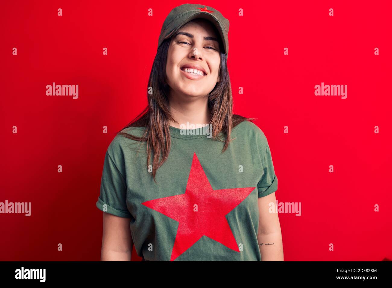 Young beautiful brunette woman wearing cap and t-shirt with red star ...