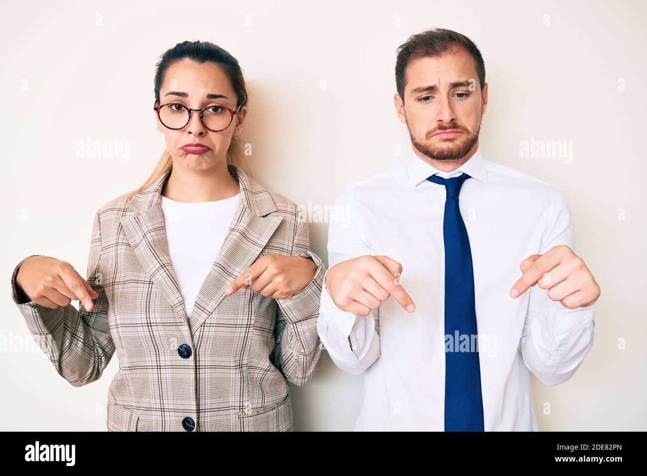 Beautiful couple wearing business clothes pointing down looking sad and ...