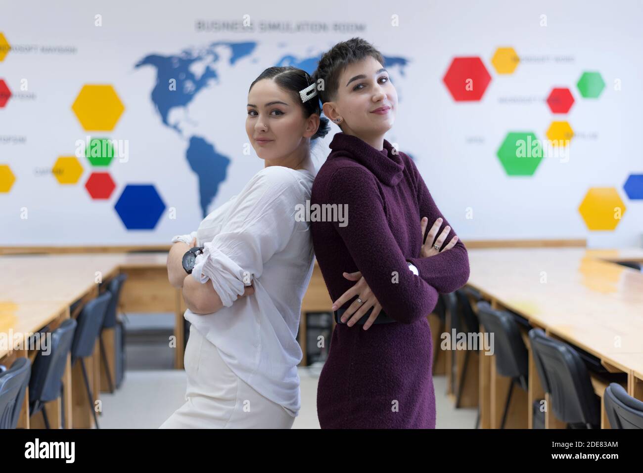Two college students standing inside classroom and posing for ...