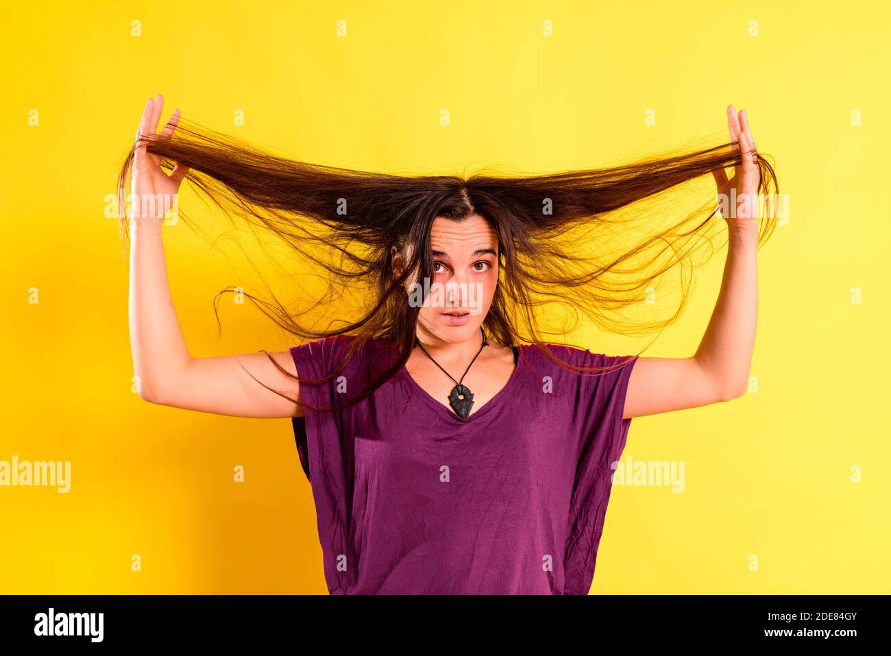 Young woman tangling her hair with her hands in disgust with her ...
