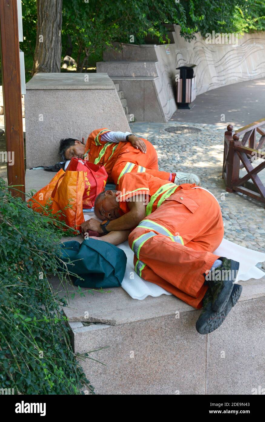 Two workers take a lunchtime nap on a shady bench in Nanguan park in ...