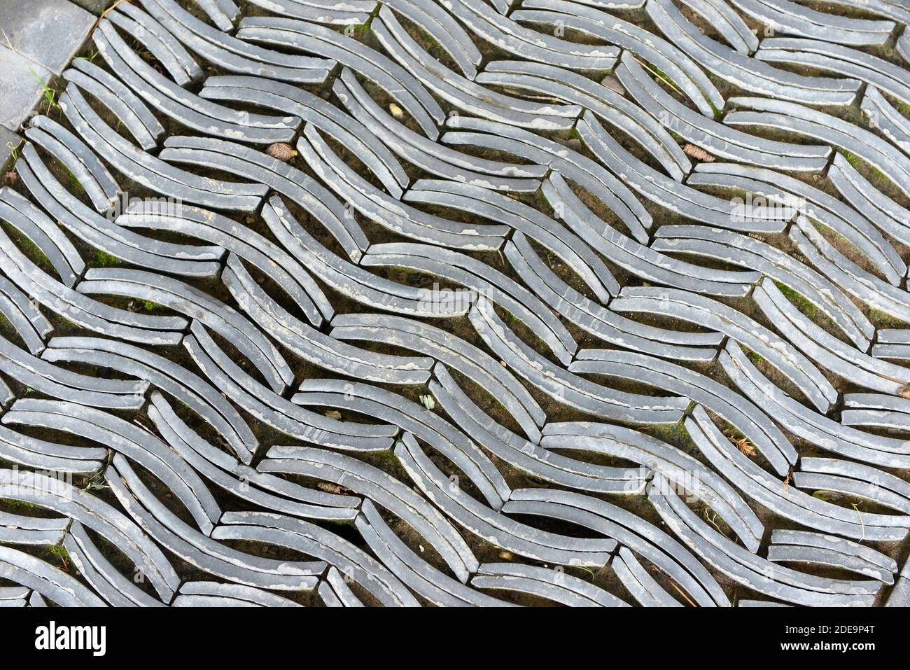 Unusual paving made from upturned roofing tiles placed on their edges ...
