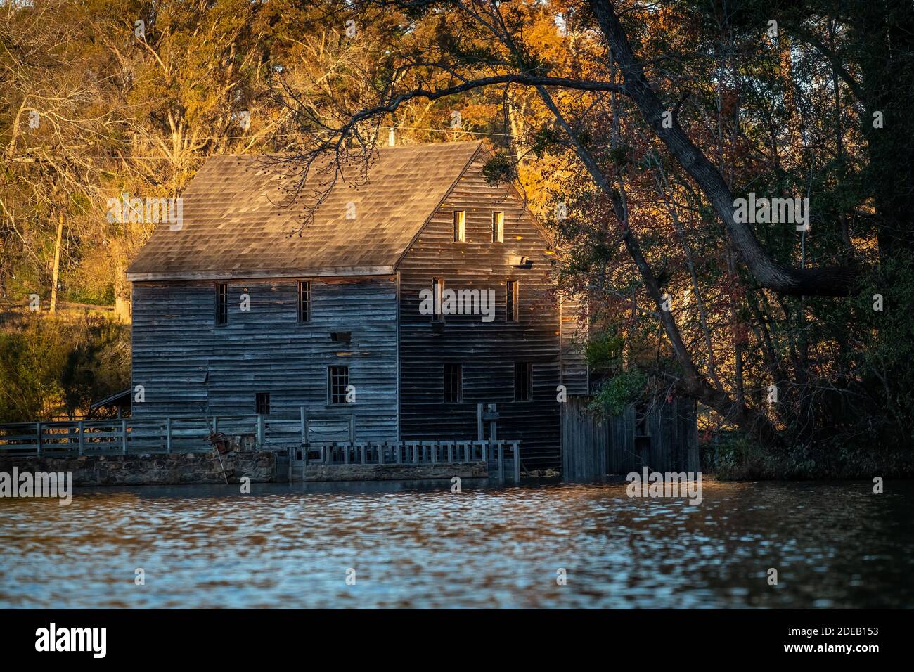View of the old gristmill from across the millpond during golden hour ...