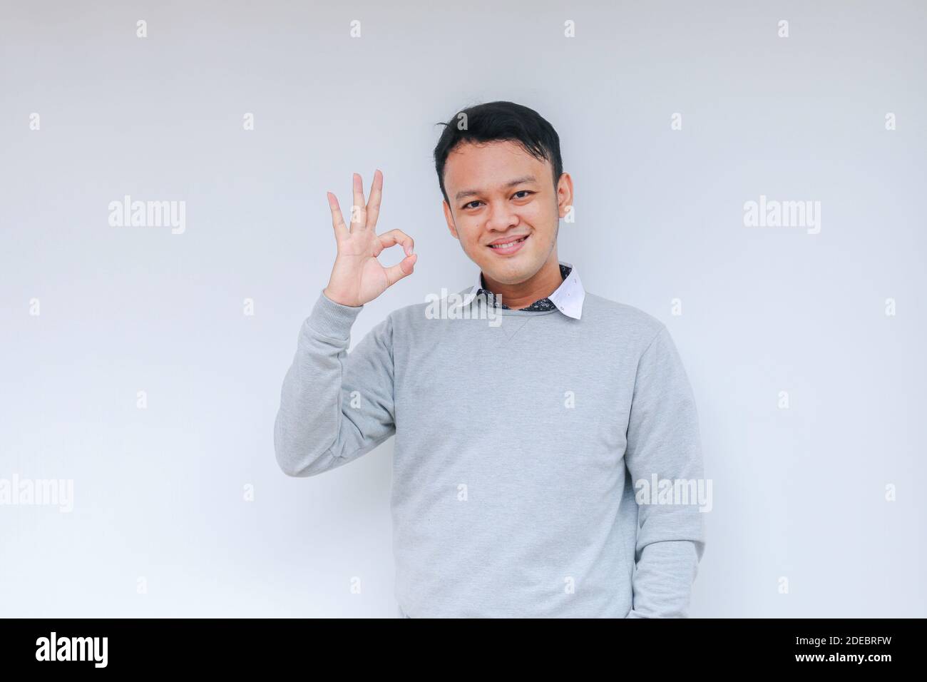 Young Asian man wear grey shirt with happy smiling face and thumbs up ...